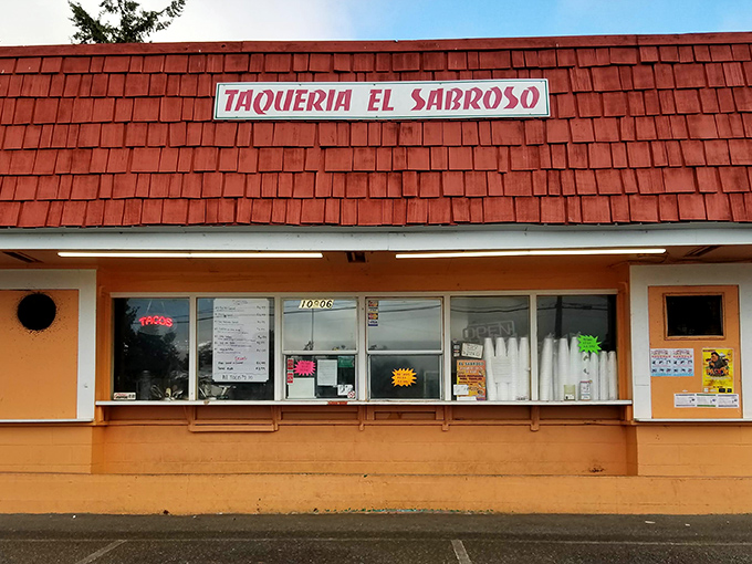 The red-roofed taqueria stands out like a culinary lighthouse, beckoning hungry travelers with its vibrant orange walls and festive papel picado banners.