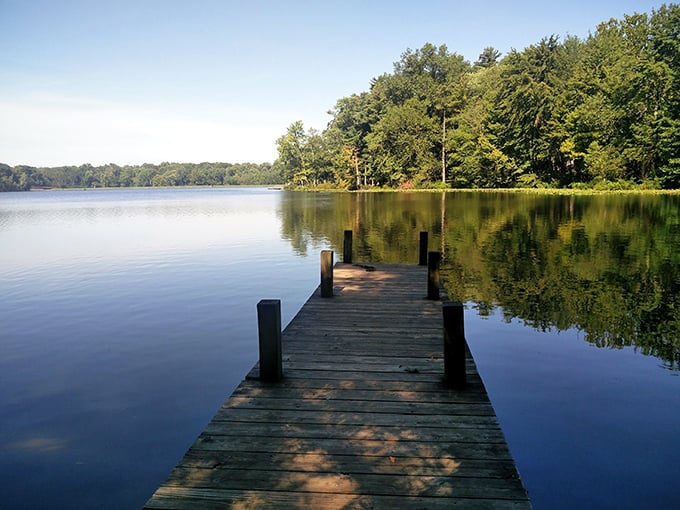 The wooden dock at Lincoln State Park invites contemplation as it stretches into the glassy waters, offering a front-row seat to nature's daily masterpiece.