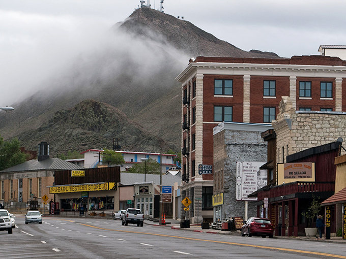 Main Street Tonopah greets visitors with historic brick buildings while fog dramatically embraces the mountain, like nature's own theater curtain rising on a mining town stage.