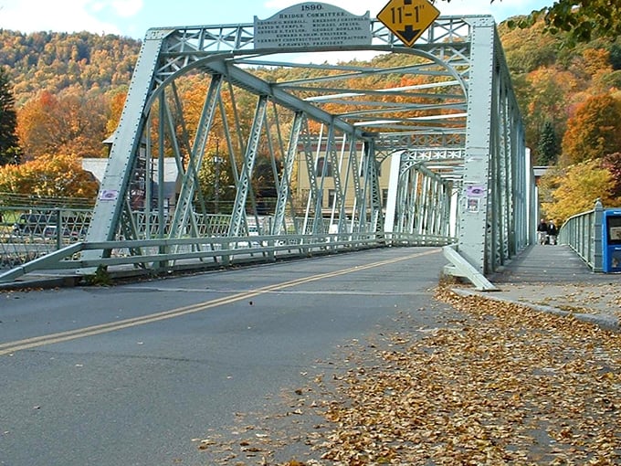 The 1890 Truss Bridge stands as an industrial-age masterpiece, autumn leaves scattered like nature's confetti celebrating its enduring design.