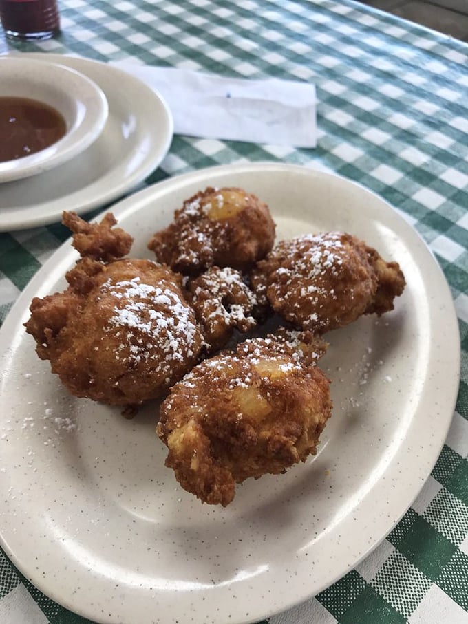 Apple fritters dusted with powdered sugar—like delicious little meteorites that crash-landed perfectly on your breakfast plate.