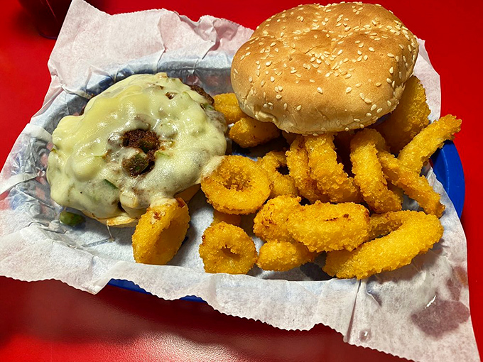 A burger that demands to be photographed before being devoured, flanked by golden onion rings that shatter satisfyingly with each bite.