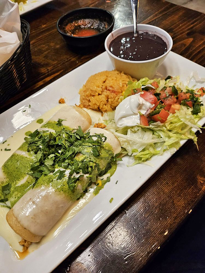 A plate that tells a story: cilantro-kissed enchiladas, perfectly seasoned rice, and beans so good they deserve their own fan club.