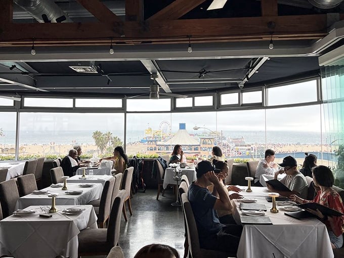 The dining room buzzes with conversation while floor-to-ceiling windows remind everyone why oceanfront real estate commands those prices.