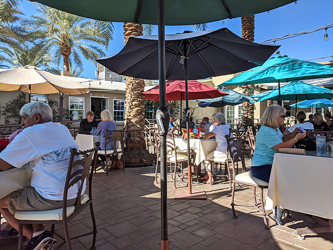 The outdoor dining area offers shaded respite from desert heat. Palm trees and umbrellas create the perfect setting for date-infused indulgence.