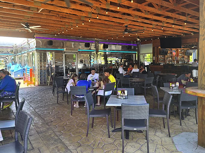 The outdoor seating area hums with the energy of satisfied diners swapping stories while Florida sunshine filters through wooden beams overhead.