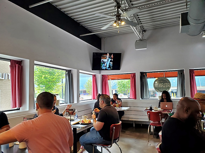 Sunlight streams through red-curtained windows as diners engage in the sacred ritual of the weekend brunch gathering.