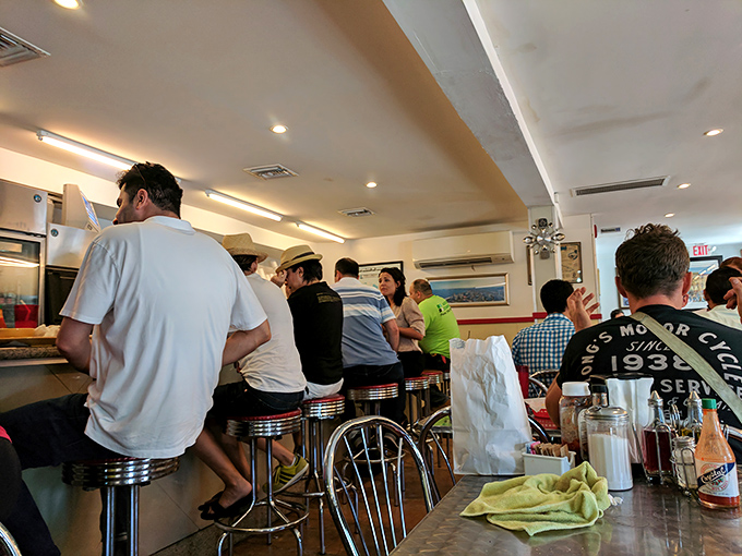 The lunch counter ballet: locals perched on chrome stools, performing the time-honored ritual of sandwich appreciation with practiced expertise.