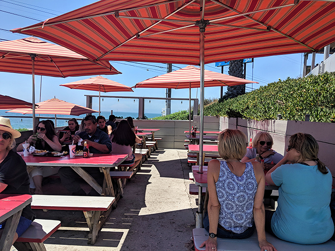 Under striped umbrellas with ocean views, strangers become temporary friends united by the universal language of "pass the tartar sauce."