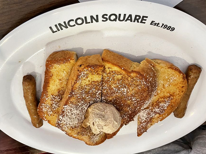 French toast that's achieved golden-brown perfection, dusted with powdered sugar and crowned with a scoop of butter that's slowly creating a river of deliciousness.