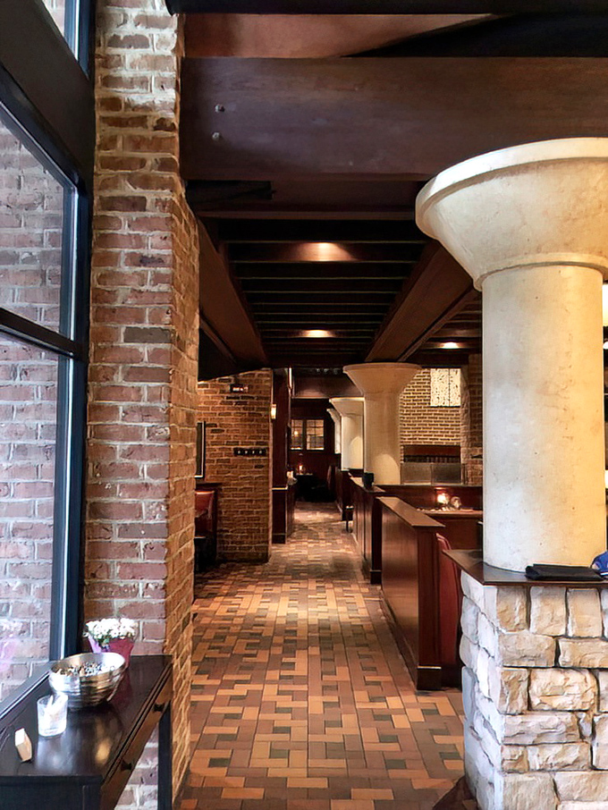 Stone columns and brick archways create dining spaces that feel like sophisticated wine cellars designed for memorable conversations.