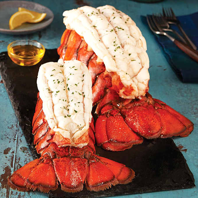 Ocean treasures on a slate canvas. These lobster tails aren't just seafood; they're sculptures of deliciousness that make you forget you're miles from any coastline.