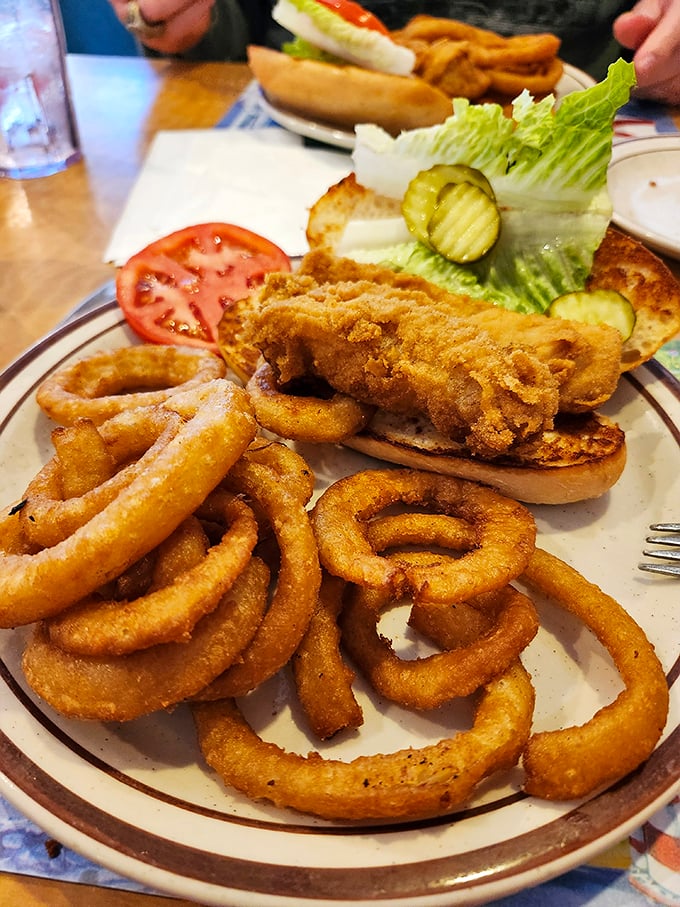A chicken sandwich surrounded by an army of onion rings. This isn't just lunch &ndash; it's a fortress of fried goodness that demands your full attention.