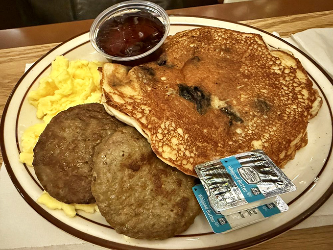 The breakfast trinity &ndash; golden pancakes, savory sausage, and scrambled eggs &ndash; presented on the restaurant industry's most iconic plate design.