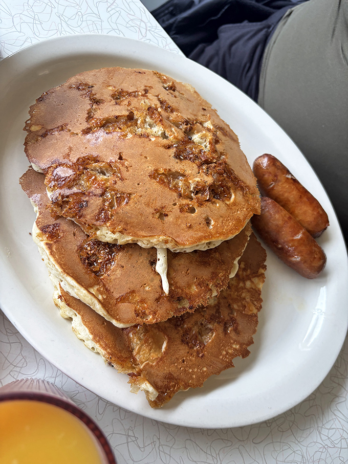Pancakes stacked higher than your weekend expectations, with sausages standing guard against anyone trying to share your plate.