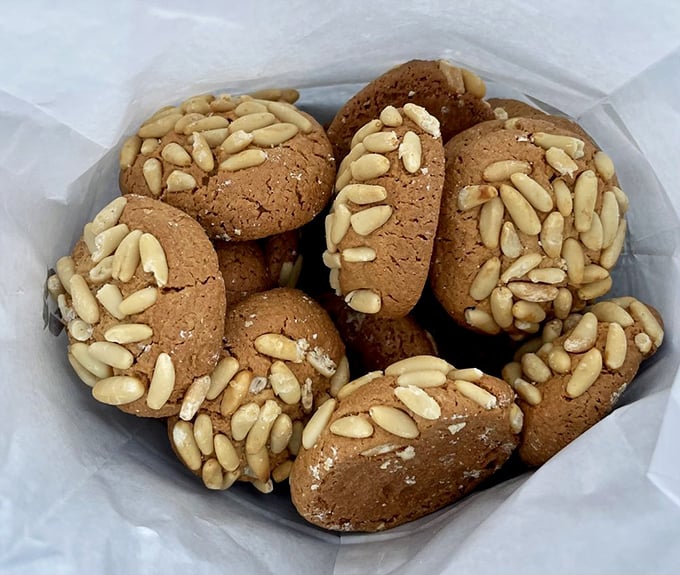 Pignoli cookies huddle together like old friends at a reunion, pine nuts standing guard over their sweet, chewy centers.
