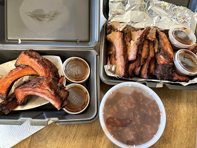 Ribs and brisket sharing a tray like old friends, with sauce containers standing by like eager wingmen ready to enhance the experience.