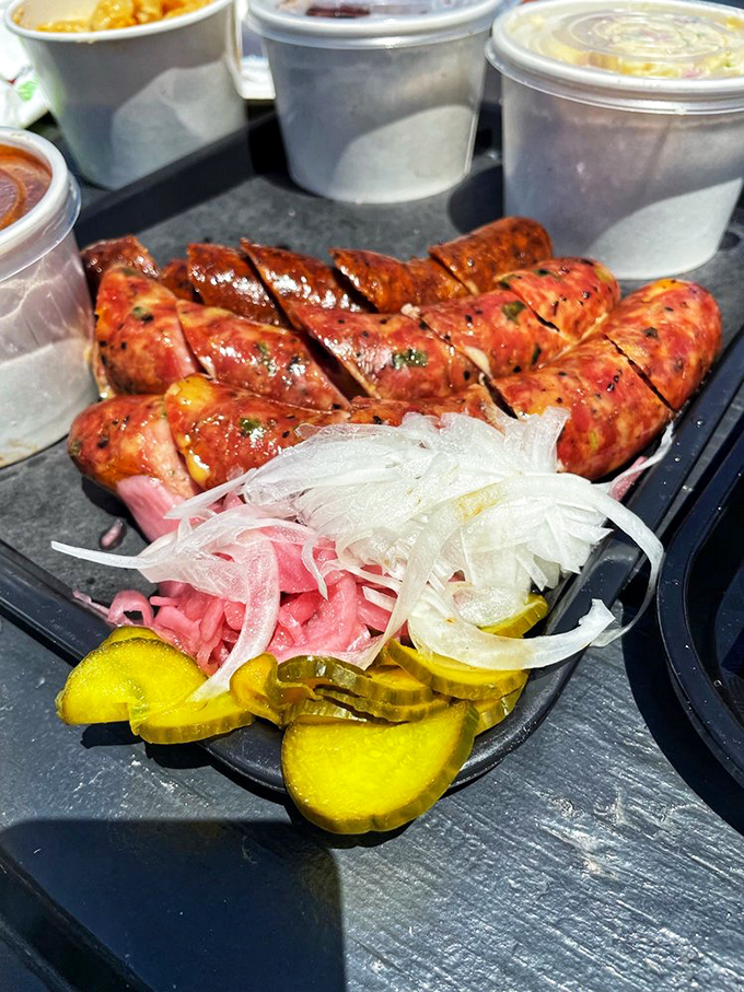 Sausages sliced to reveal their treasures within, accompanied by pickles and onions that cut through richness like witty banter at a dinner party.