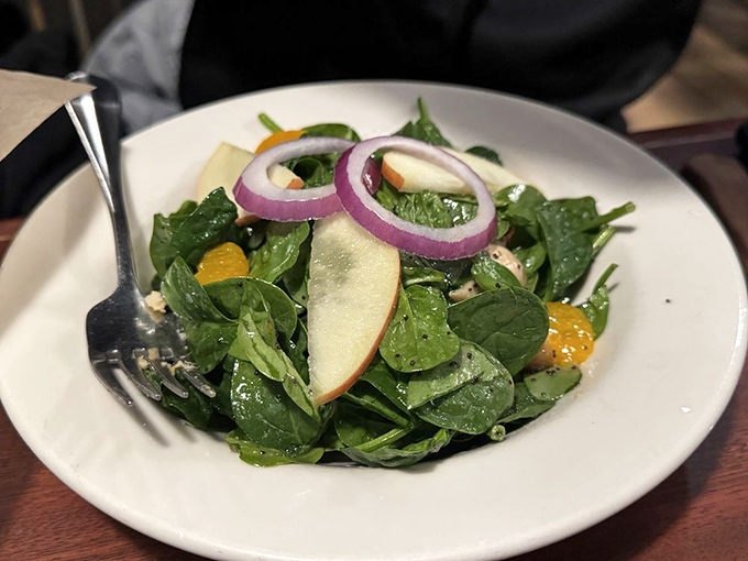Fresh spinach salad with apple slices and red onion rings&mdash;because sometimes you need something crisp before diving into the main event.