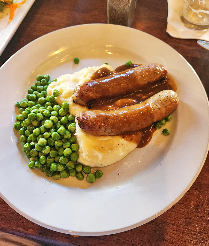Bangers and mash: where sausages lounge luxuriously atop creamy potato pillows, surrounded by peas that add both color and conscience.