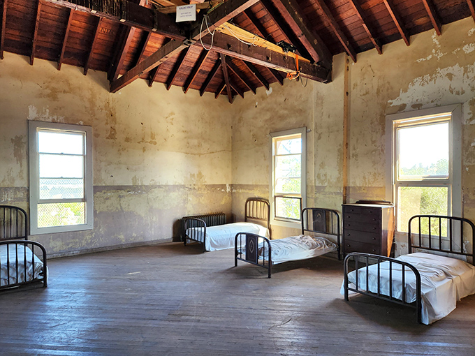 Another dormitory room where young men once dreamed of freedom beneath exposed wooden beams, the simple iron beds a reminder of institutional uniformity.