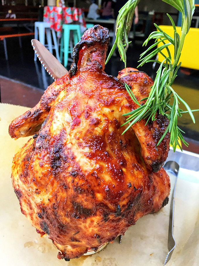 The Beer Can Chicken arrives like a showstopper, skin crackling with flavor, meat juicy beneath, and that sprig of rosemary adding a touch of elegance.