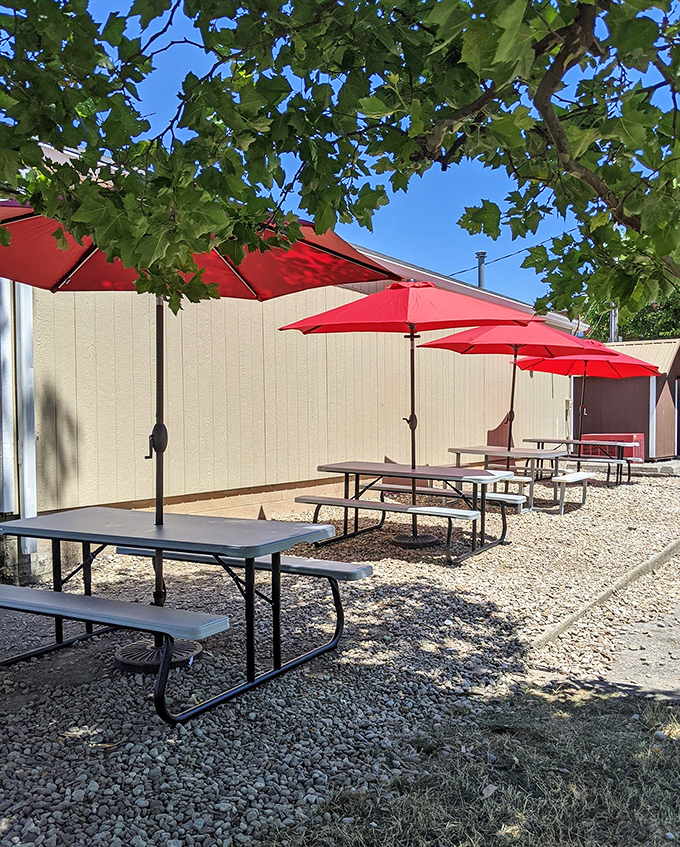 Outdoor seating under cheerful red umbrellas. These picnic tables have hosted more summer memories than your family photo album.