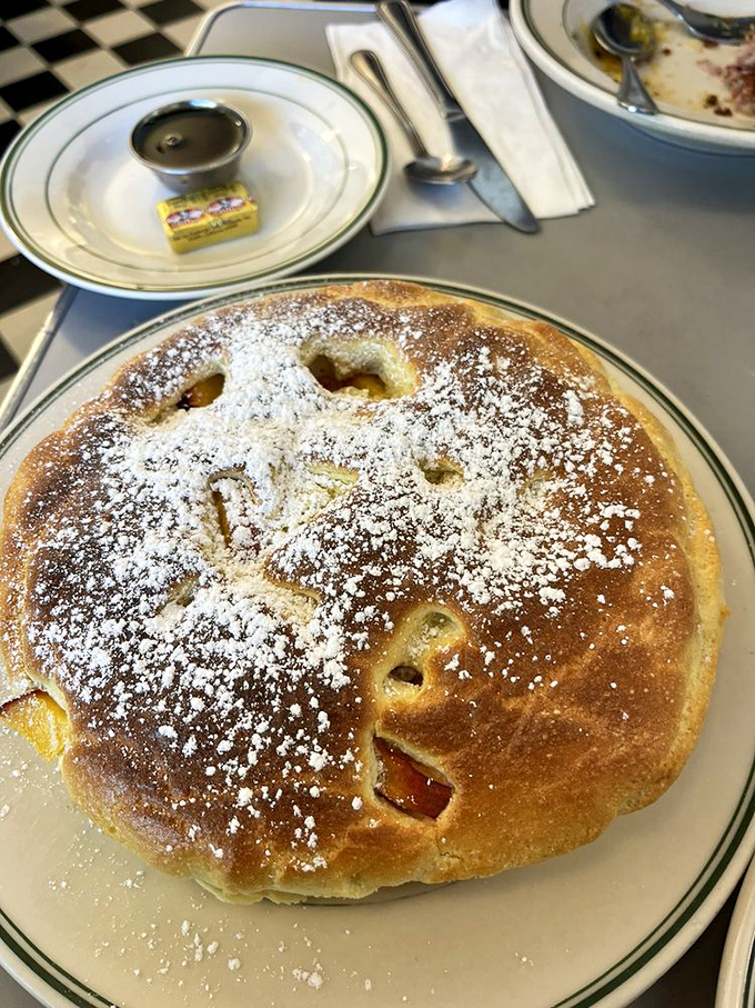 This pancake isn't just breakfast&mdash;it's dessert in disguise, with fruit peeking through like hidden treasures under a dusting of powdered sugar.