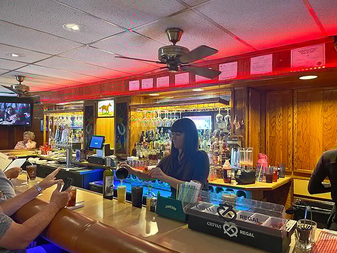 The bar glows blue like a portal to good times, where bartenders orchestrate liquid happiness and strangers become temporary friends over shared stories.