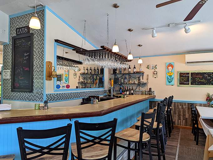 The bar area whispers "stay awhile" with its coastal blue trim and hanging glassware. That "EATS" sign might be the most honest advertising in town.