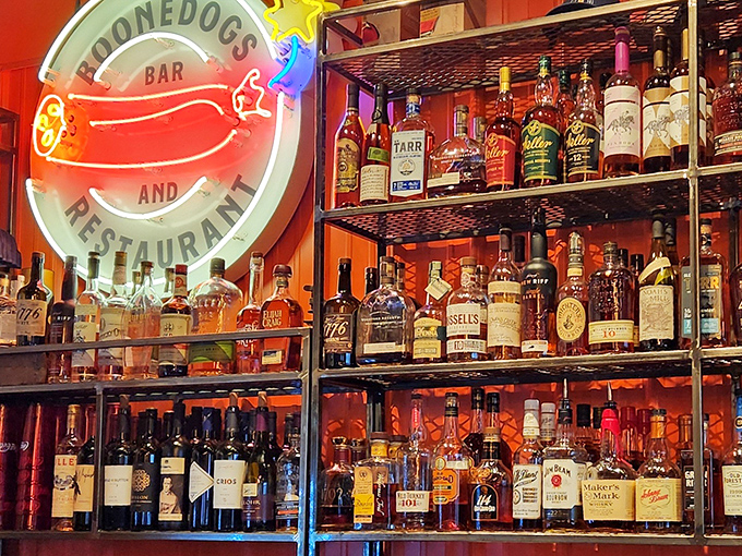 The neon hot dog sign glows like a nighttime beacon, while the bourbon collection behind the bar stands ready for exploration.