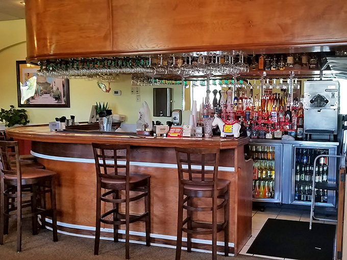 A well-stocked bar promises liquid happiness to complement your meal. The hanging glassware catches the light like crystal chandeliers for your margarita dreams.