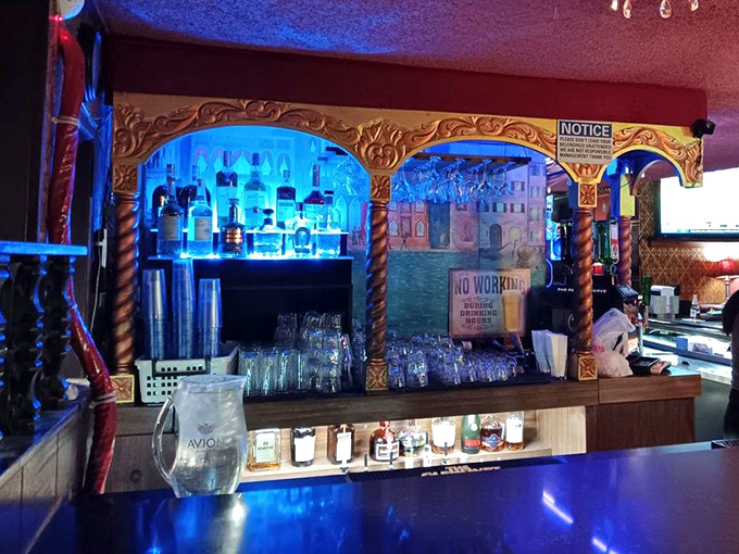 The bar's enchanted archways frame bottles like precious artifacts, bathed in blue light that makes every cocktail feel like it's being mixed in some magical realm.