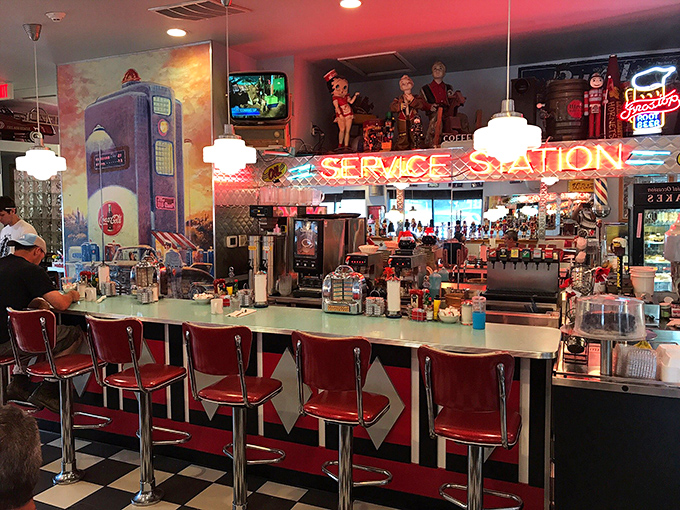 The counter seats&mdash;where solo diners become part of the show, watching short-order magic happen beneath the glow of "SERVICE STATION" neon.