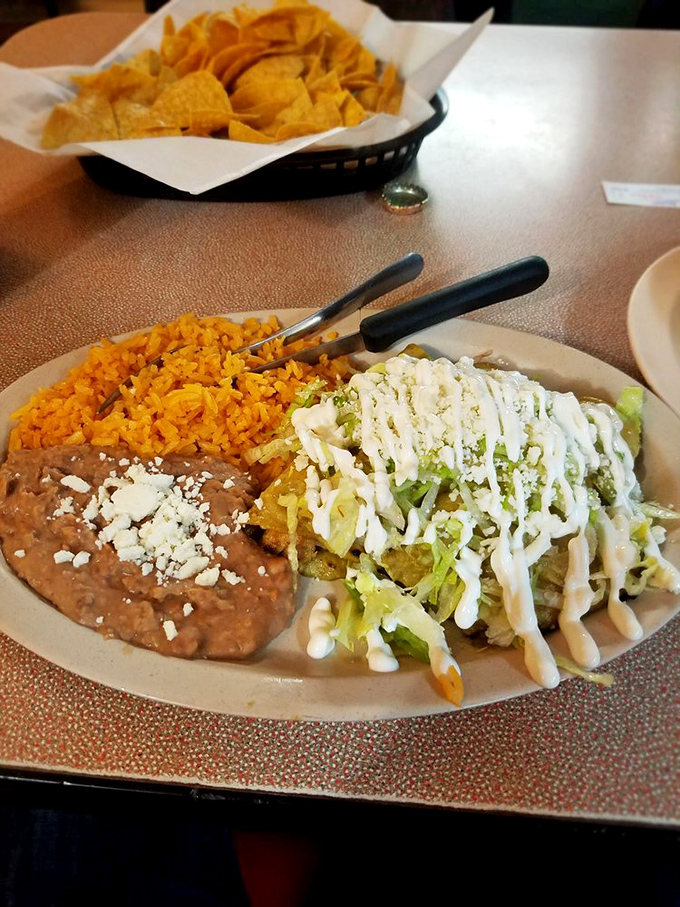 A plate that celebrates the art of sauce distribution. Those enchiladas wear their creamy green topping and rice sidekick with well-deserved pride.