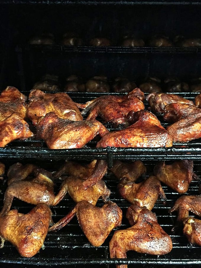 The smoker's art on full display&mdash;chicken wings and thighs getting their baptism in aromatic hardwood smoke.