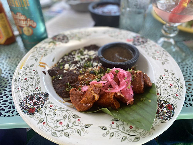Cochinita pibil presented on a plate that's as artistic as the dish itself. Those pink pickled onions add the perfect pop of color.