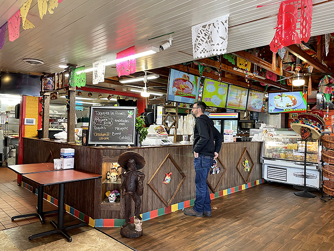 The beating heart of Taqueria Los Primos, where culinary magic happens behind the counter while papel picado flutters overhead.