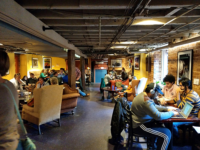 A community in comfortable chaos. Where laptops meet conversations and strangers become temporary neighbors over steaming cups.