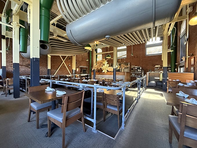 Sunlight streams through windows illuminating wooden tables where countless memorable meals have unfolded beneath industrial pipes.