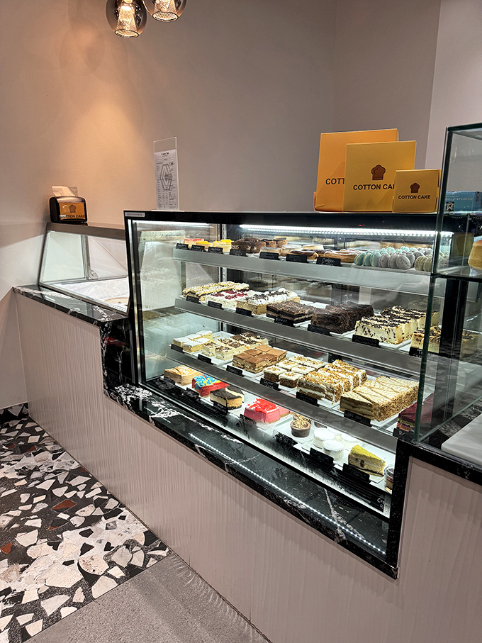 The display case&mdash;a museum of edible art where each shelf showcases desserts that belong in both your Instagram feed and your immediate future.