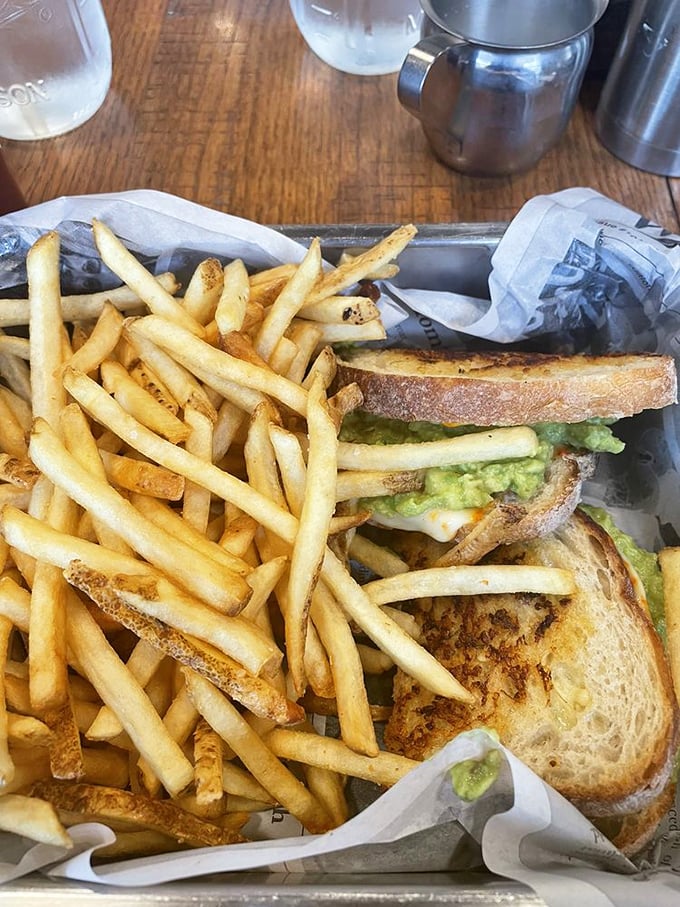 This isn't just a sandwich—it's architecture. Golden fries cascading around perfectly grilled bread hiding avocado treasures within. Lunch elevated to an art form.