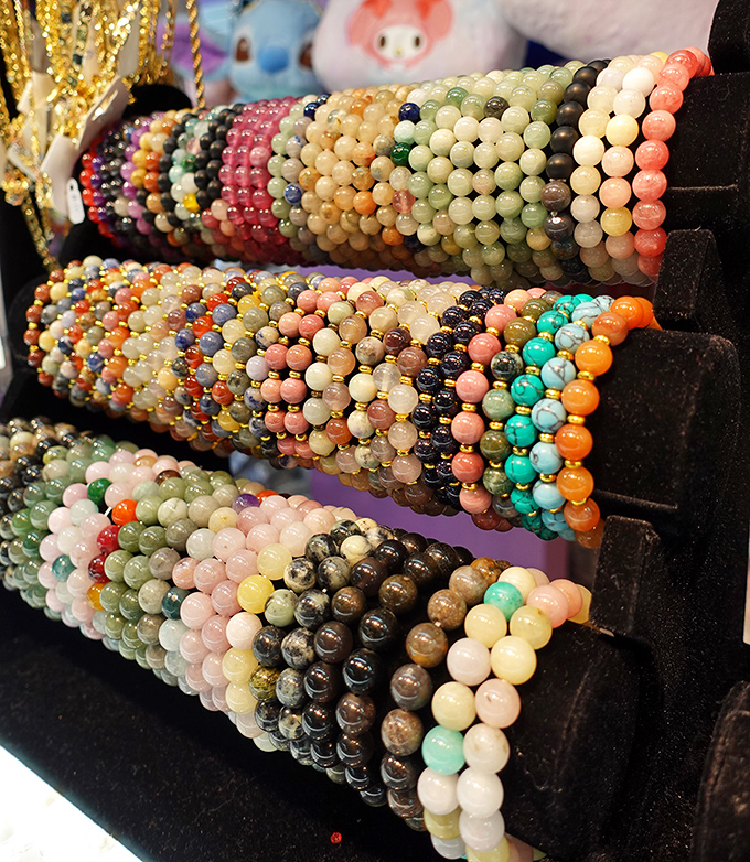 Colorful stone bracelets stacked like edible candy necklaces for grown-ups, each promising various degrees of cosmic enlightenment or at least compliments at dinner parties.