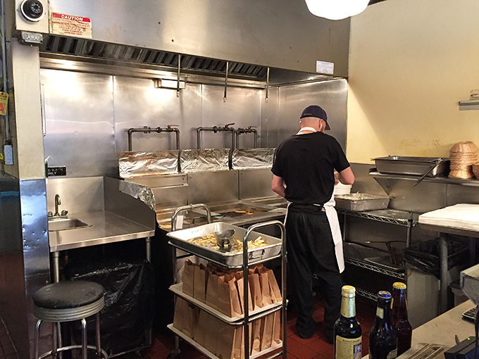 The kitchen where magic happens. Deep fryers stand ready for the next batch of perfectly battered fish in this efficient, no-nonsense cooking space.