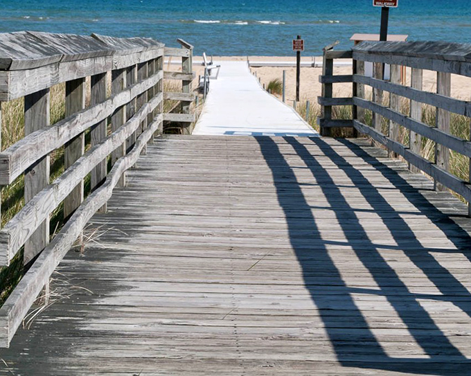 This weathered boardwalk leads to Lake Huron's endless blue horizon. Each wooden plank has felt thousands of eager footsteps rushing toward water.