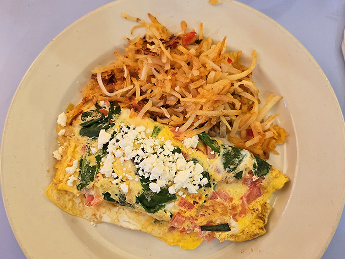 An omelet that's having a fling with feta and spinach, while crispy hash browns play chaperone on the side.