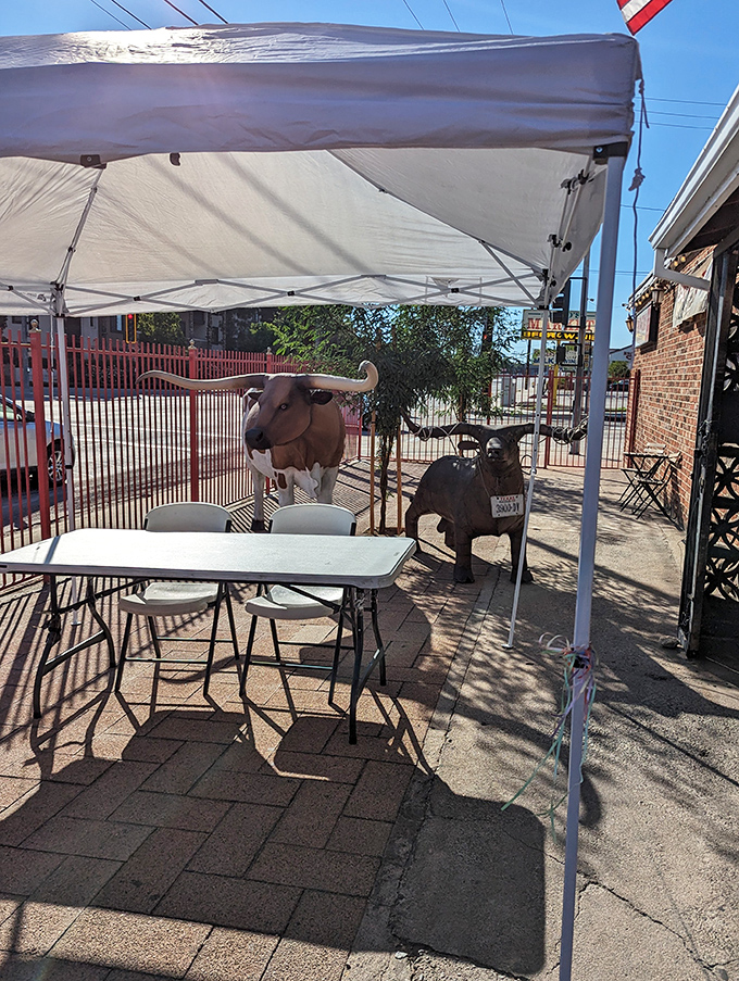 Outdoor seating guarded by metal livestock sentinels&mdash;because nothing says "authentic Texas" quite like dining under the watchful eyes of iron longhorns.