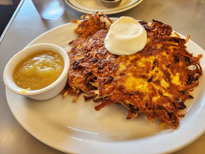 Golden potato pancakes that crackle with each bite, served with applesauce that cuts through the richness like a well-timed punchline.