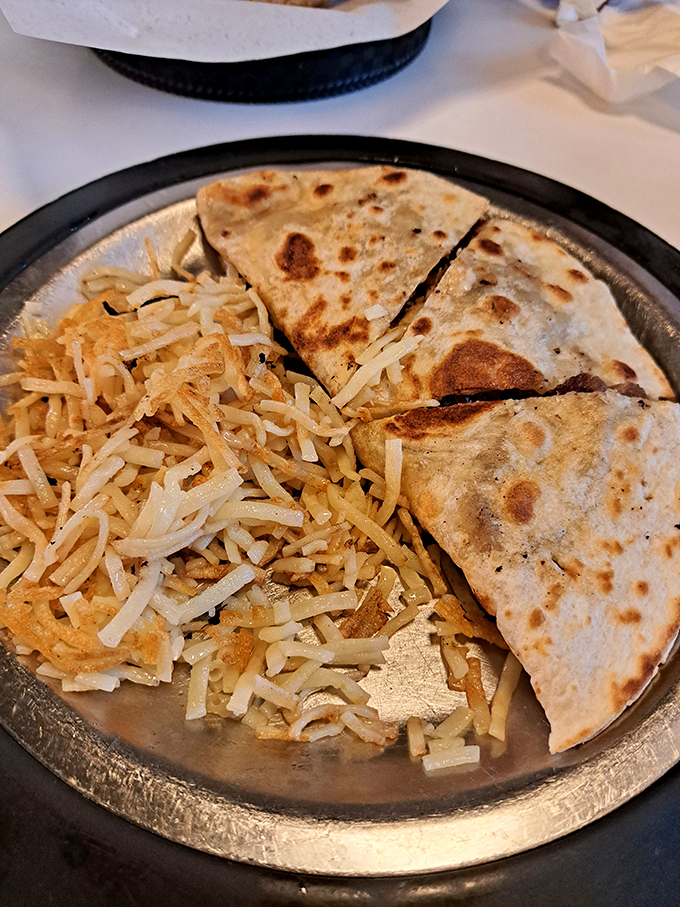 The quesadilla arrives sizzling and golden, cheese escaping from the edges like it's making a delicious prison break.