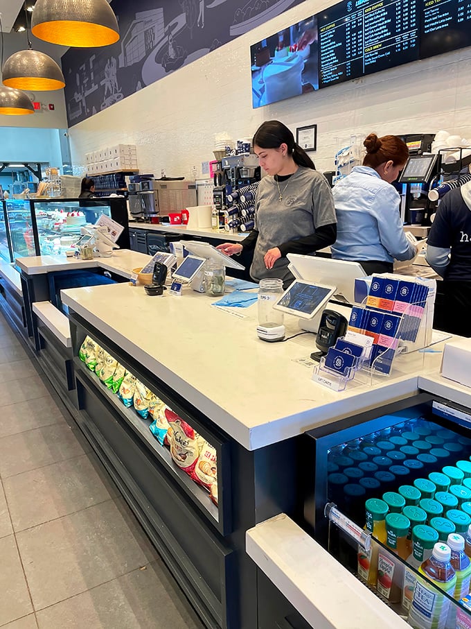Behind the counter, staff members orchestrate the daily ballet of coffee and pastry with efficiency that never sacrifices the warmth of genuine service.